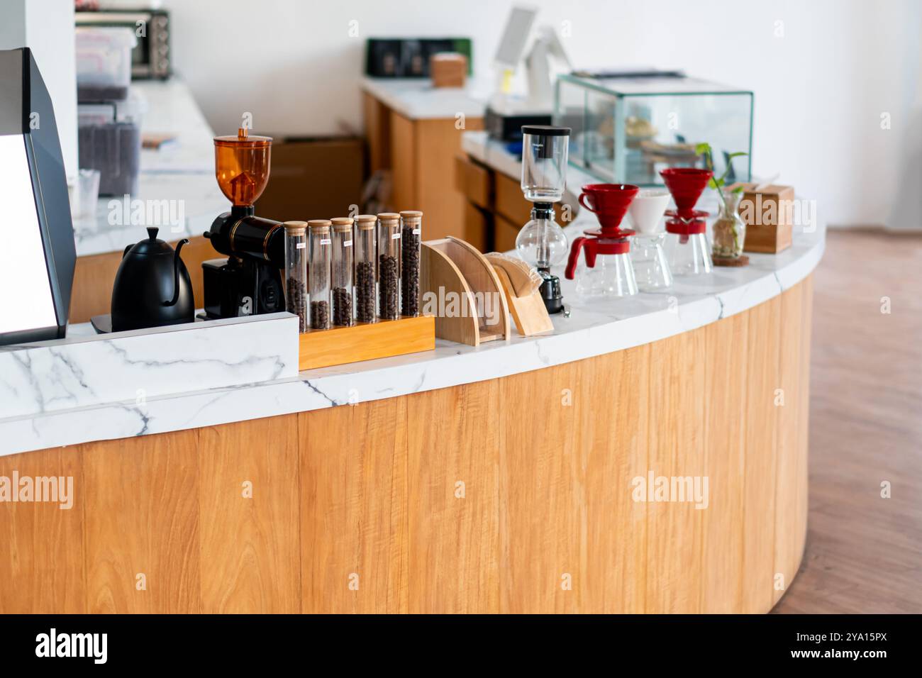 A modern coffee shop counter featuring a sleek wooden design. There are ...
