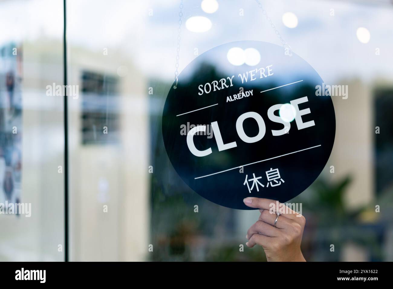 A hand holding a round sign that reads sorry We're Already CLOSE in ...
