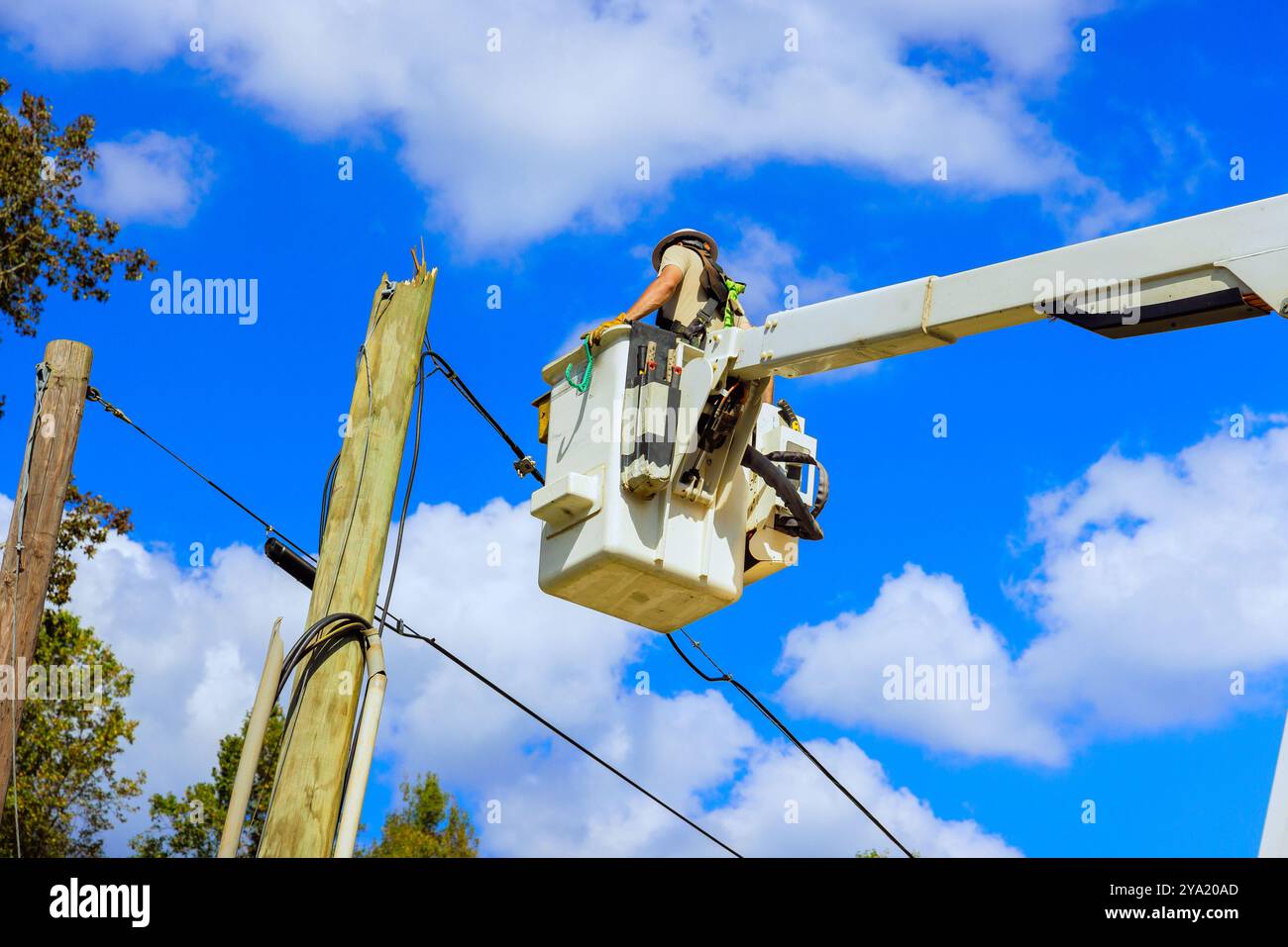 Technician repairs power line pole using hydraulic tower mounted bucket ...