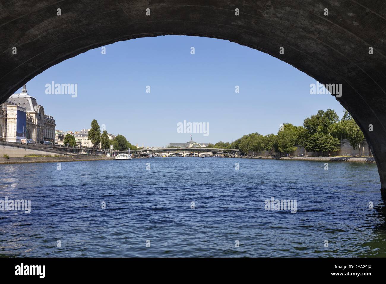 View through an arched bridge onto a river with a city background ...