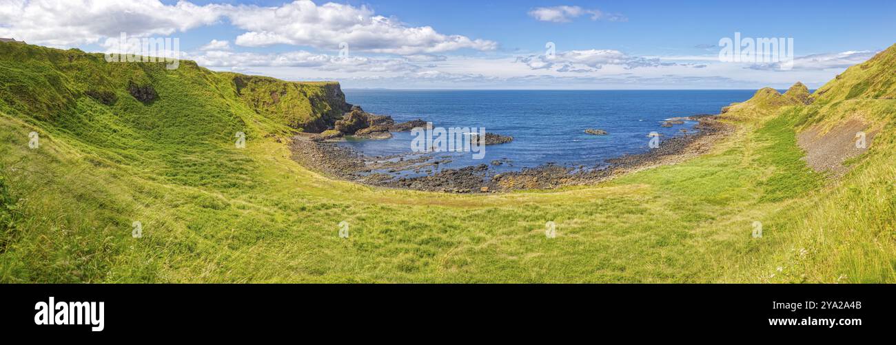 Green meadows meet the coast with a view of the sea under a blue sky ...