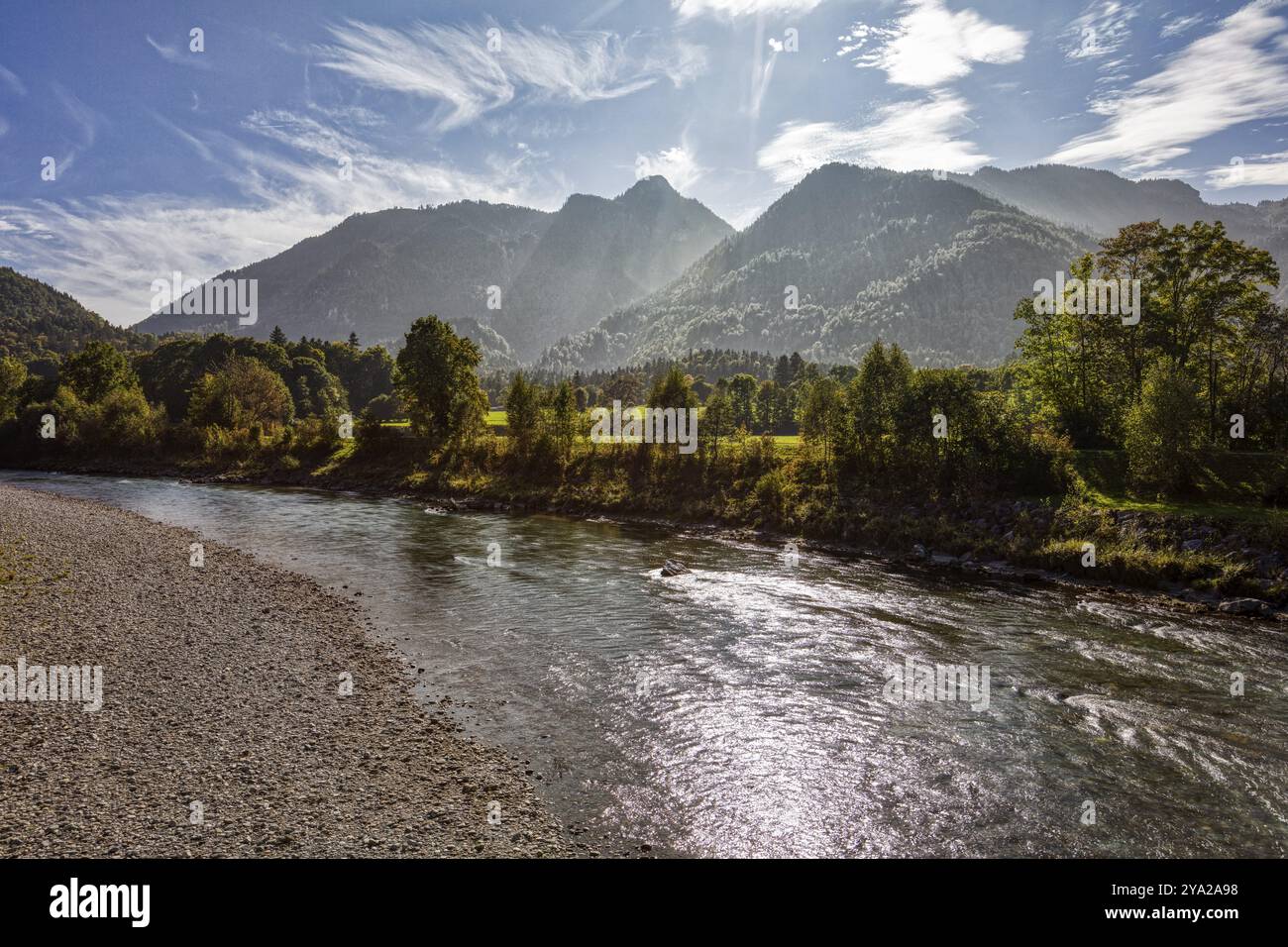 A clear river flows through an open landscape with a mountain in the ...