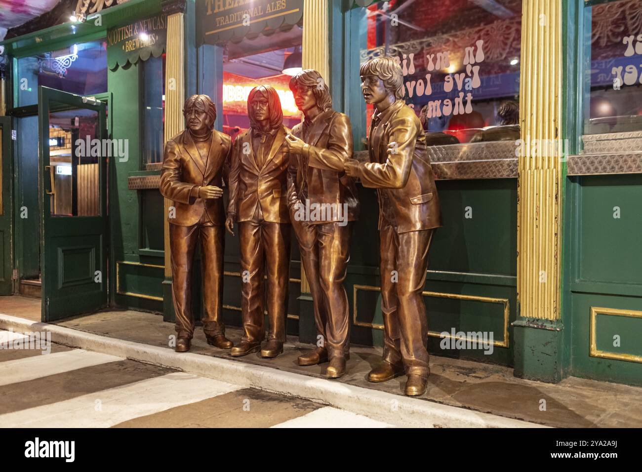 Bronze statues of four people in front of a traditionally decorated ...