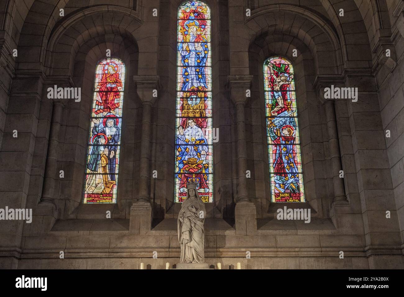 Stained glass windows illuminate a statue in a church, warm light ...