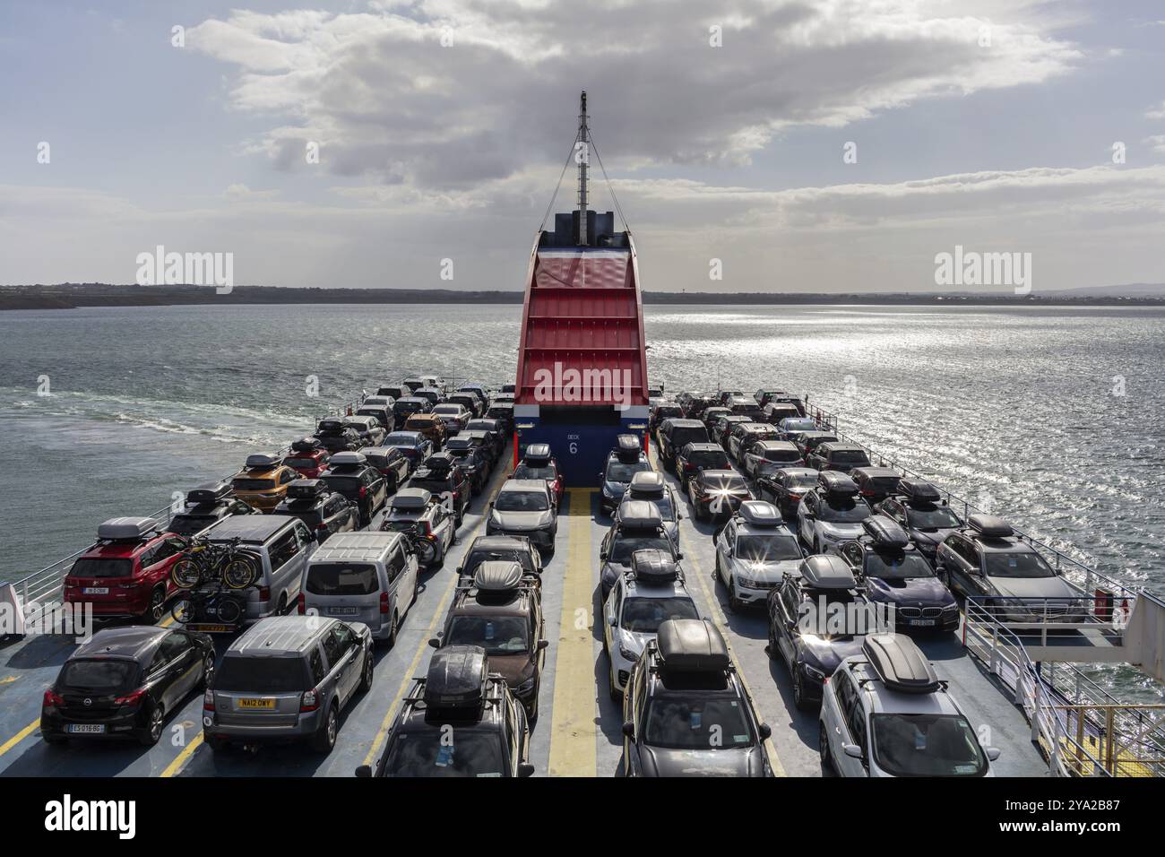 Ferry loaded with cars, sun reflected on the sea, bright sky in the ...