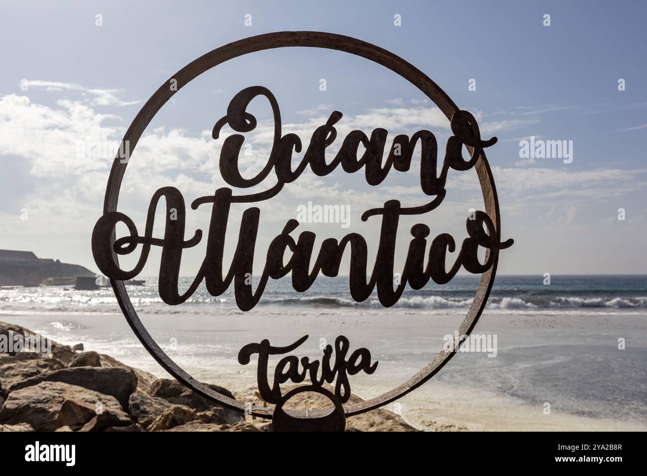 Metallic sign with lettering in front of undulating ocean and blue sky ...