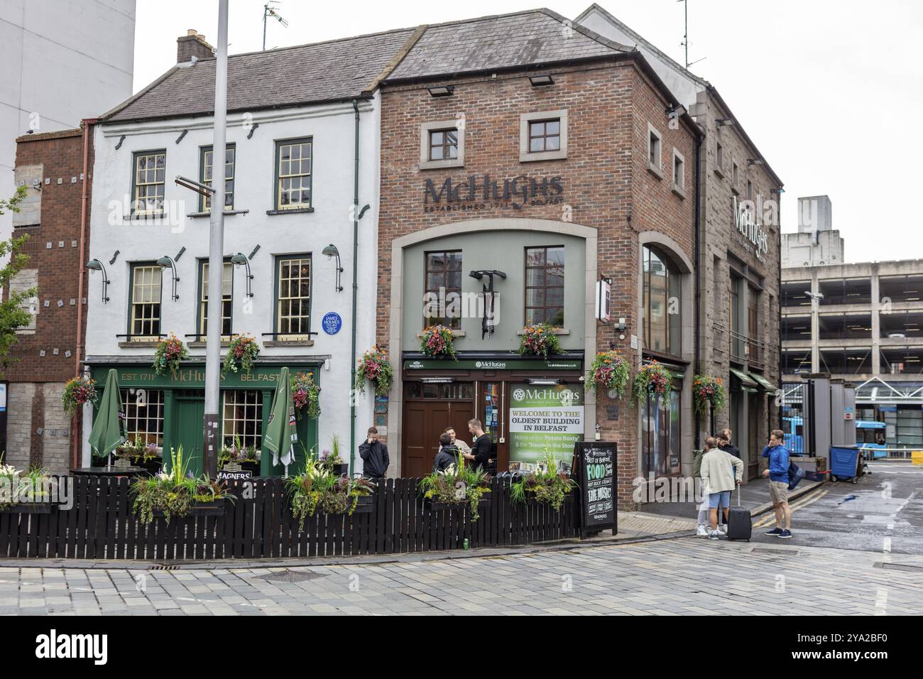 Historic pub building with flower-bedecked entrances and passers-by on ...