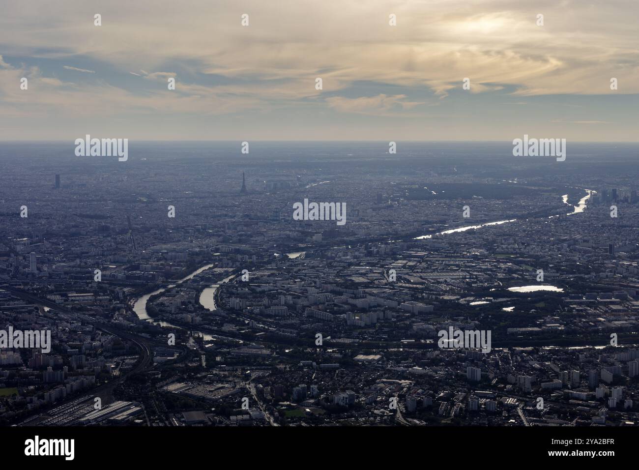 River meanders through the city under a dramatically cloudy sky, flight ...