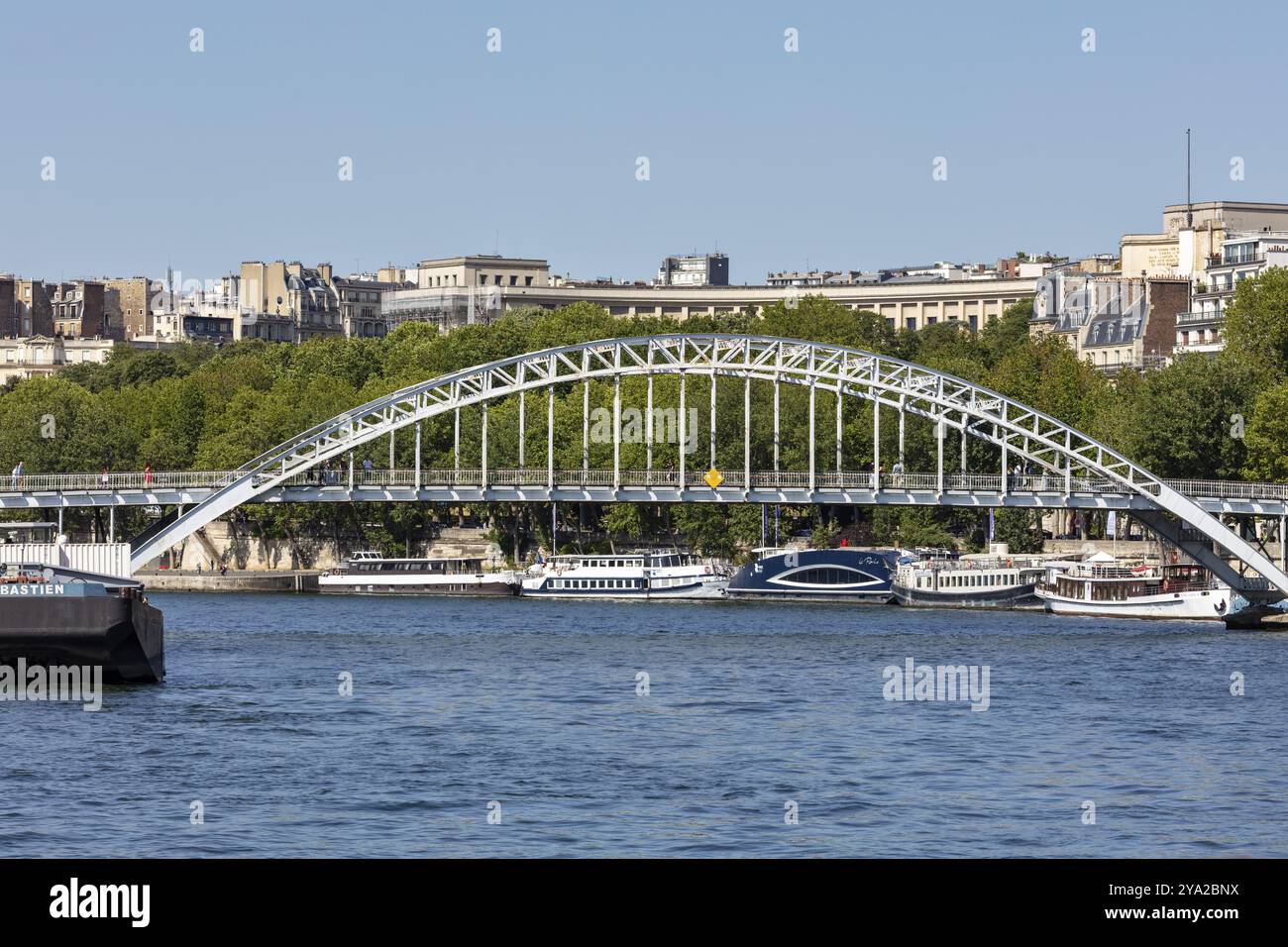Iron bridge with ships underneath, flanked by trees in an urban ...