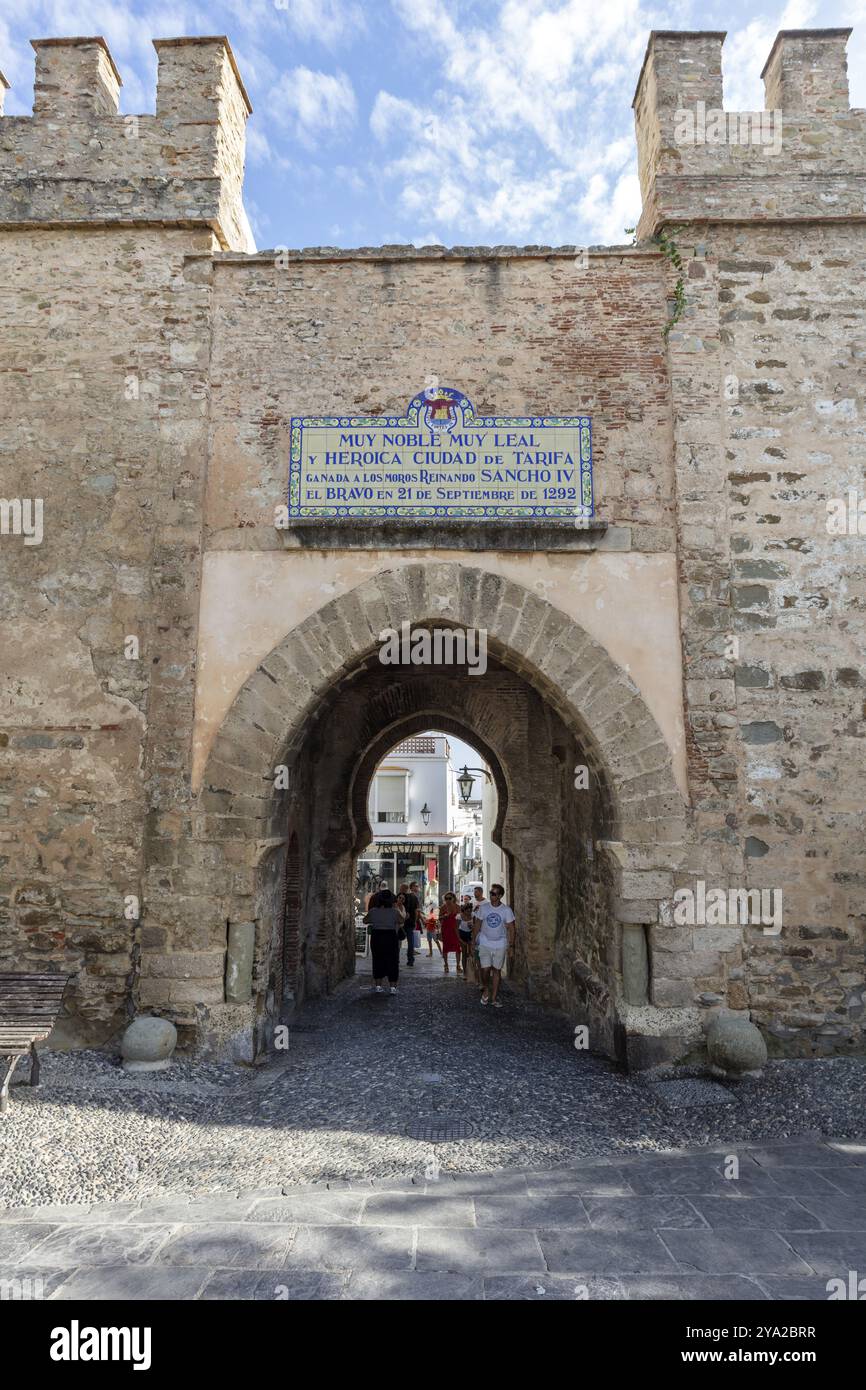 Old city gate with stone walls and a passage through which people walk ...