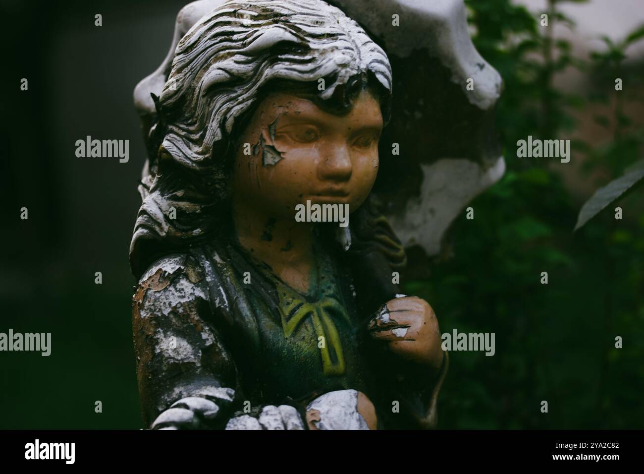 Worn stone angel. Vintage female figurine with shabby paint on her face ...