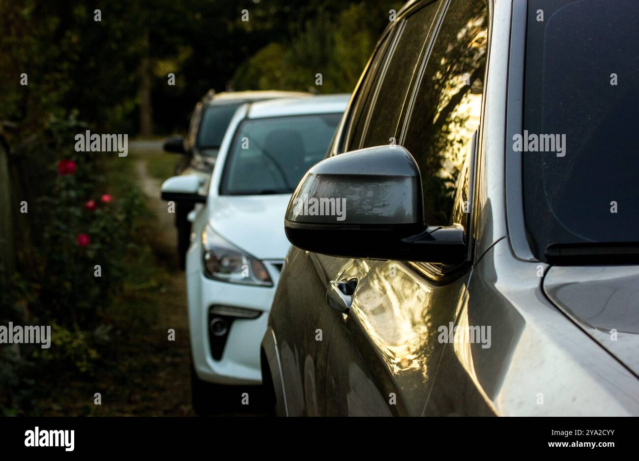 Side view of cars parked one after another on a country road, village ...