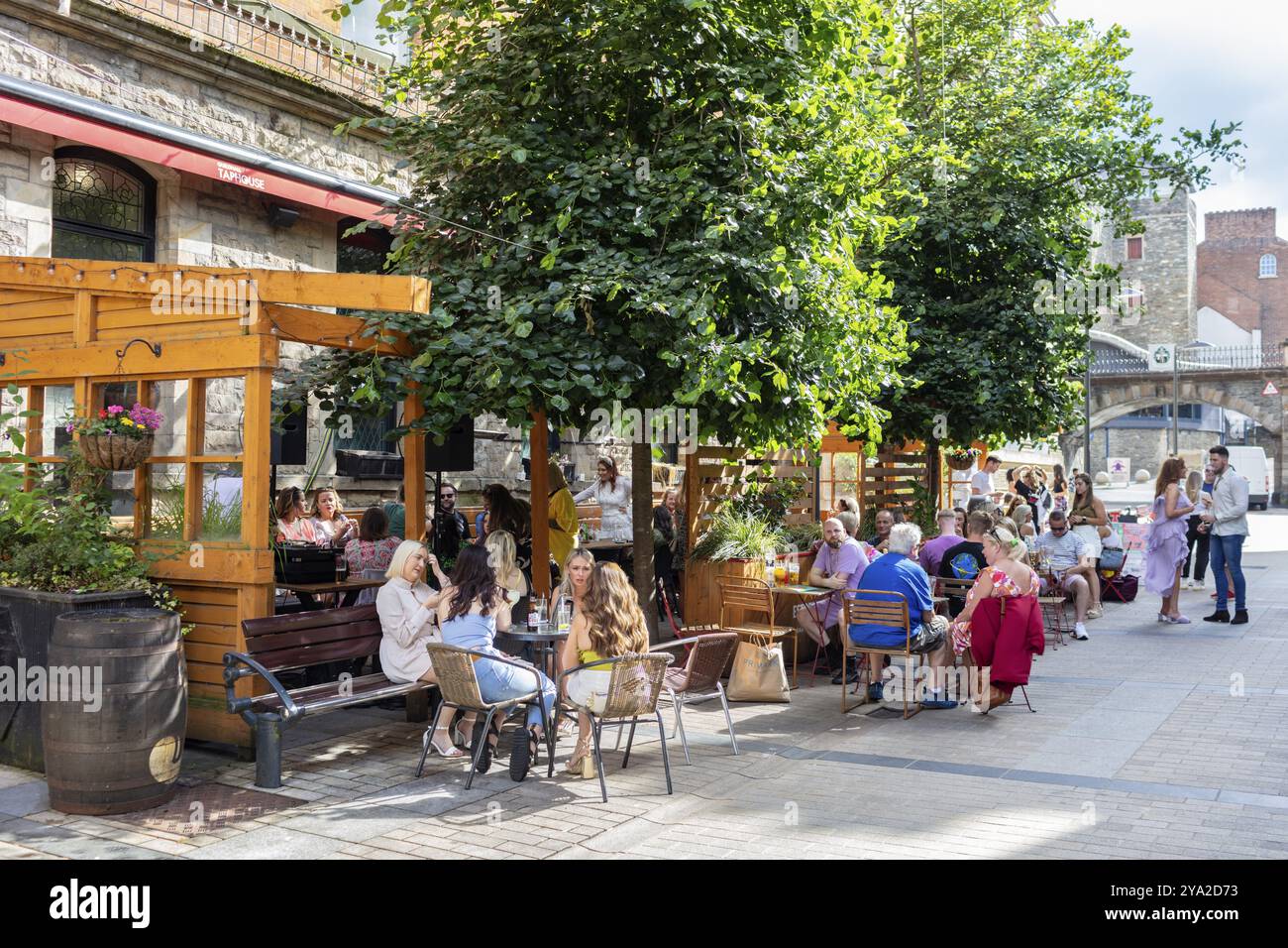 A lively street cafe with lots of people sitting and chatting outside ...