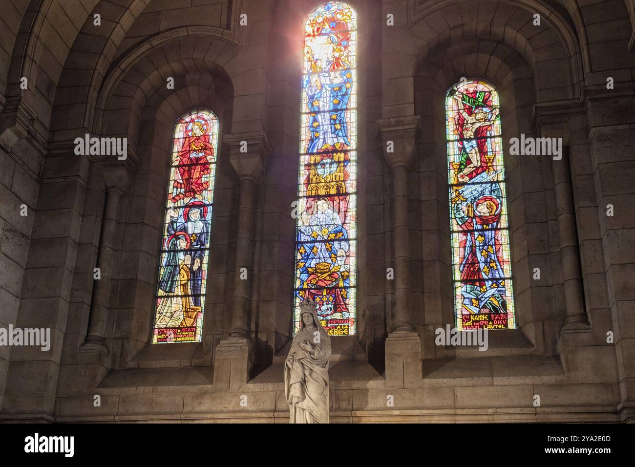 Three colourful windows with a statue in front of them, sunlight ...
