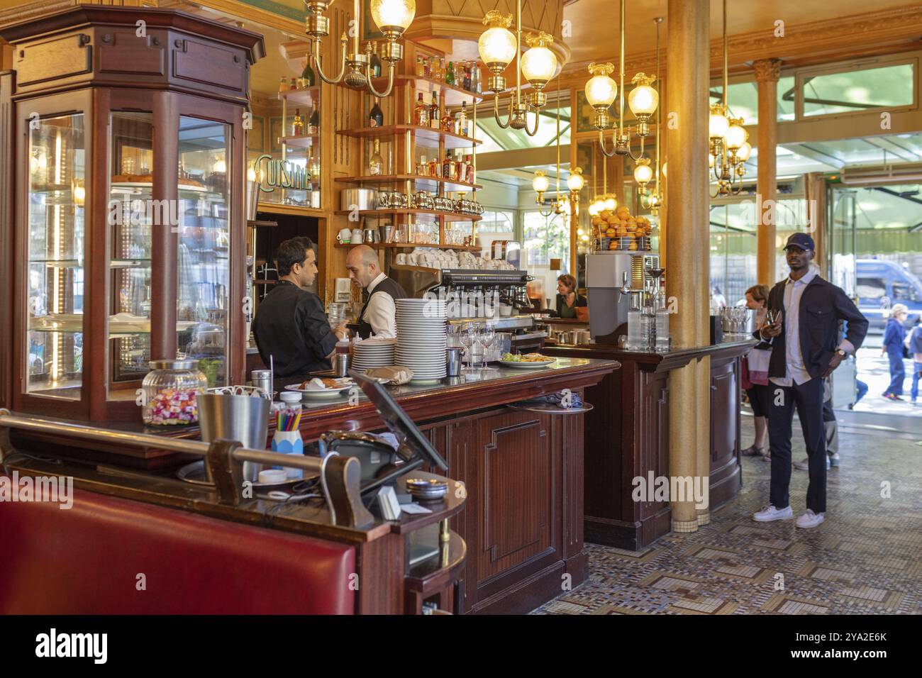 Elegant cafe with busy staff behind a glass-topped wooden counter ...