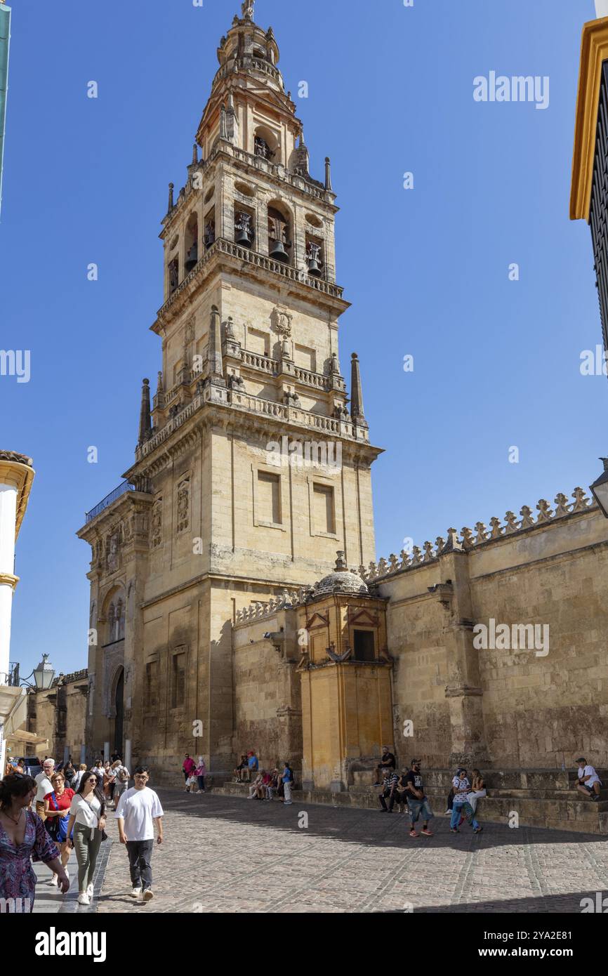 High bell tower of a historic building with people and blue sky as ...