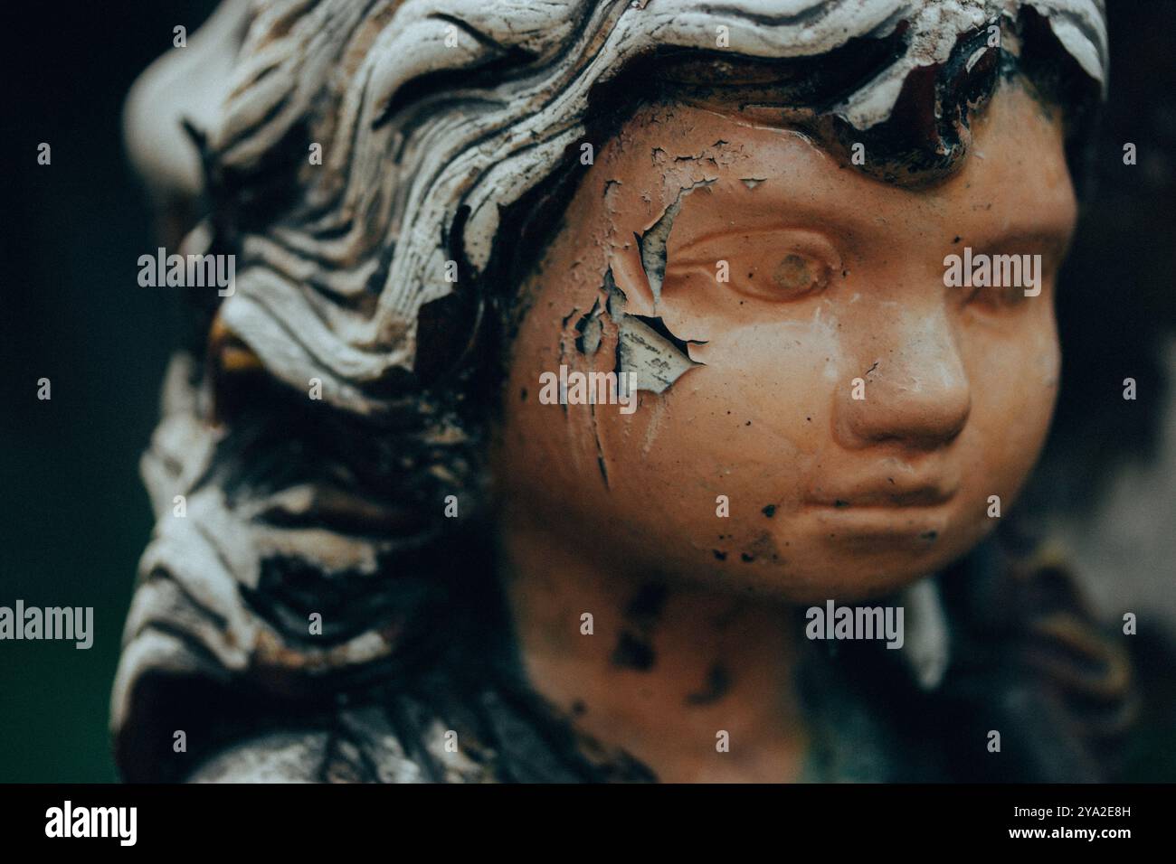 Worn stone angel. Vintage female figurine with shabby paint on her face ...