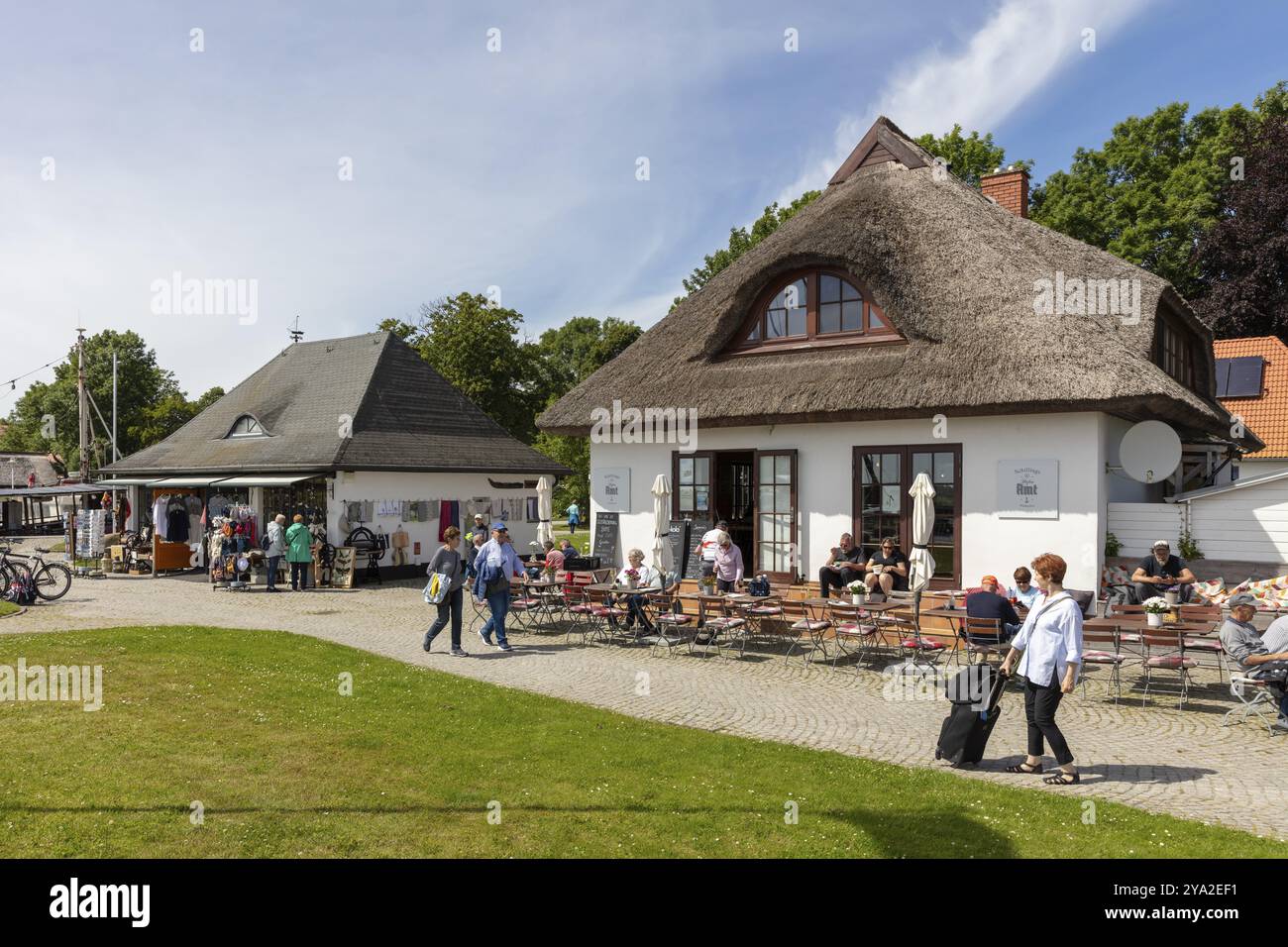 Lively cafe with people sitting outside, surrounded by thatched-roof ...
