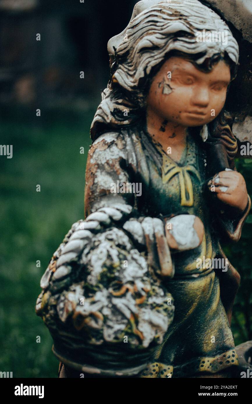 Worn stone angel. Vintage female figurine with shabby paint on her face ...