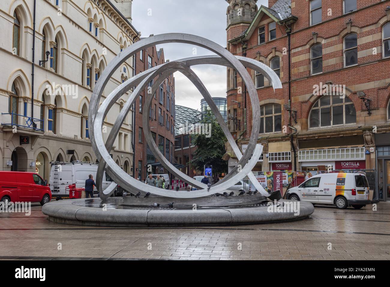 Modern sculpture in a busy street scene with people and buildings ...