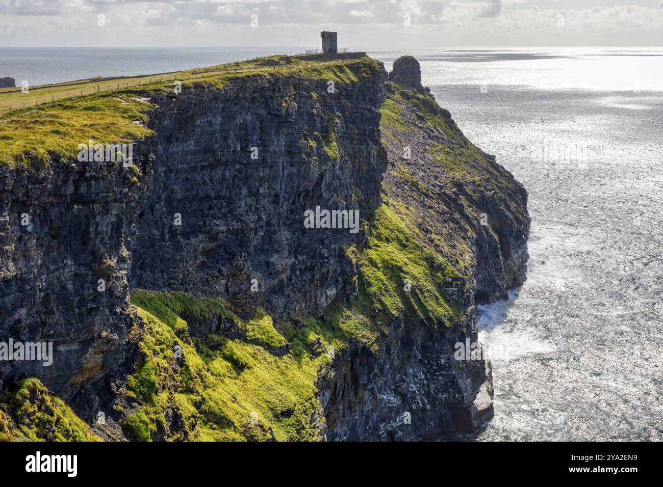 High cliffs on the horizon with an old tower surrounded by foaming sea ...