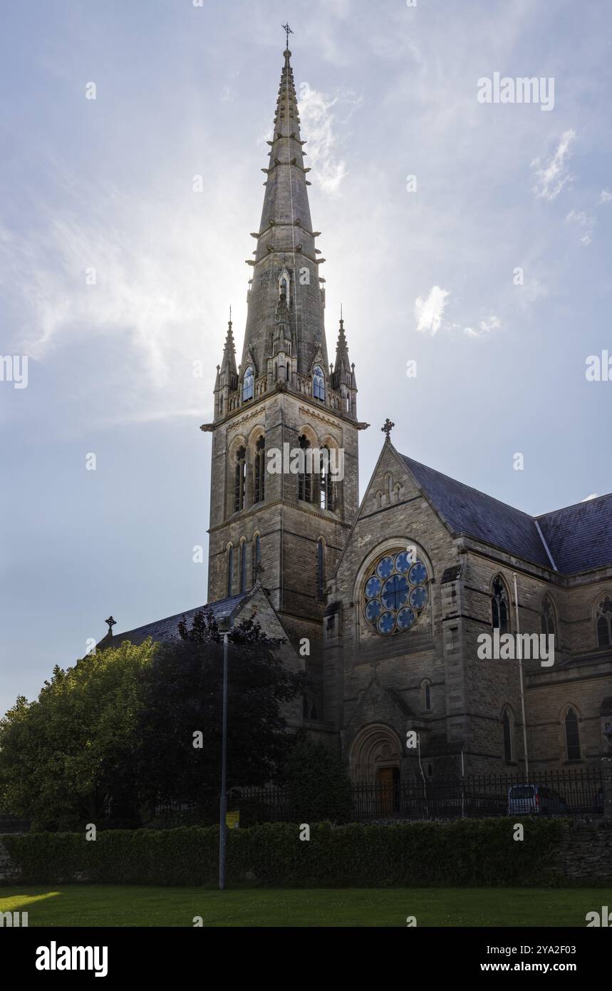 Tall Gothic church tower rising into the sky with surrounding trees and ...