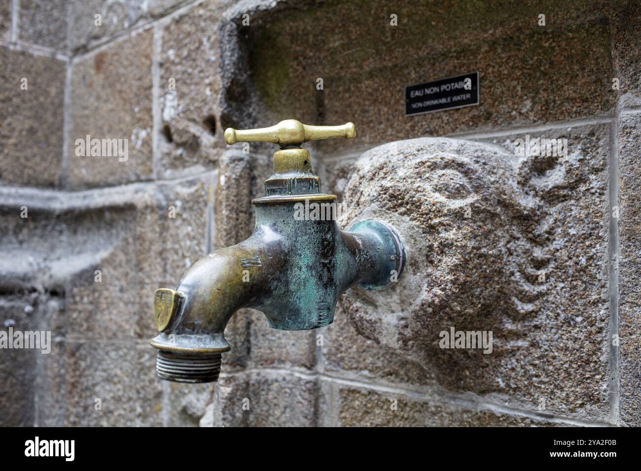 Old metal water tap on a weathered stone wall, Le Mont-Saint-Michel ...