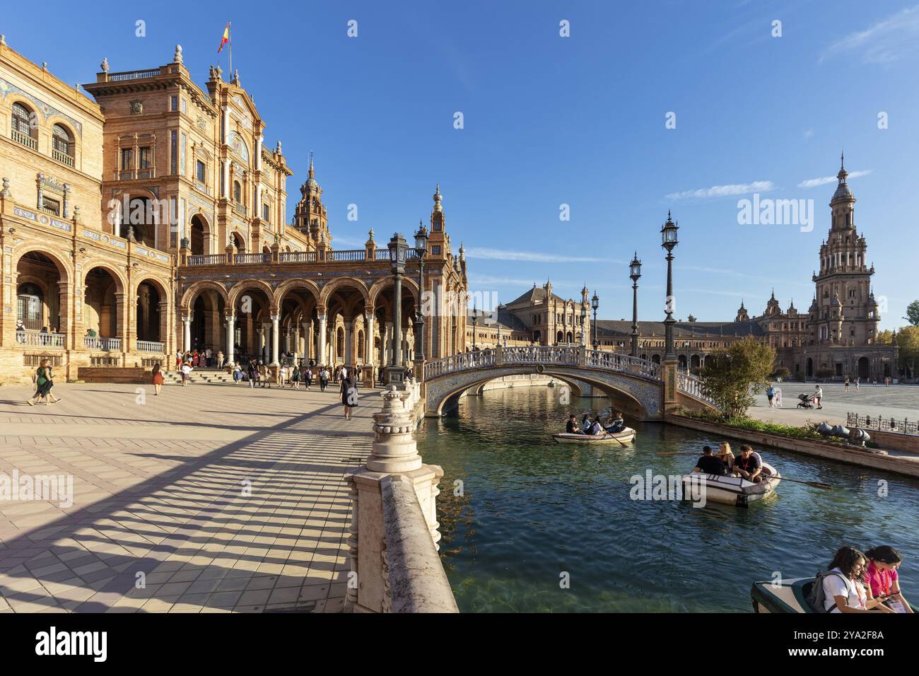 People enjoying boat rides on the water next to a curved bridge under ...