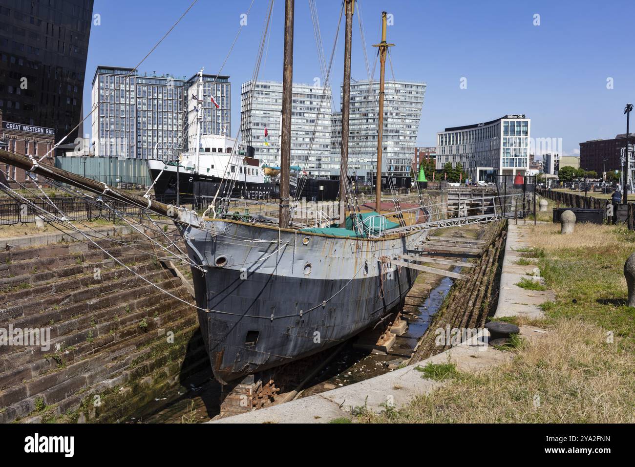 Historic sailing ship moored in the harbour, surrounded by industrial ...