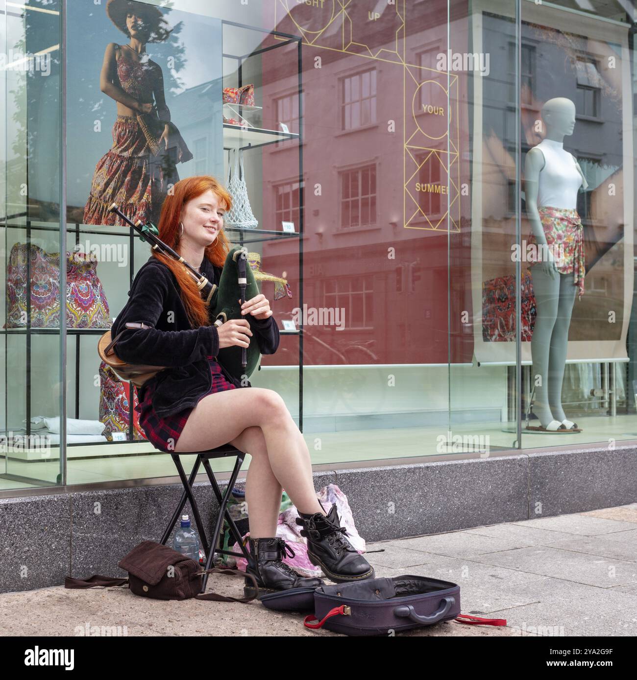 Young woman with red hair sitting and playing bagpipes in front of a ...