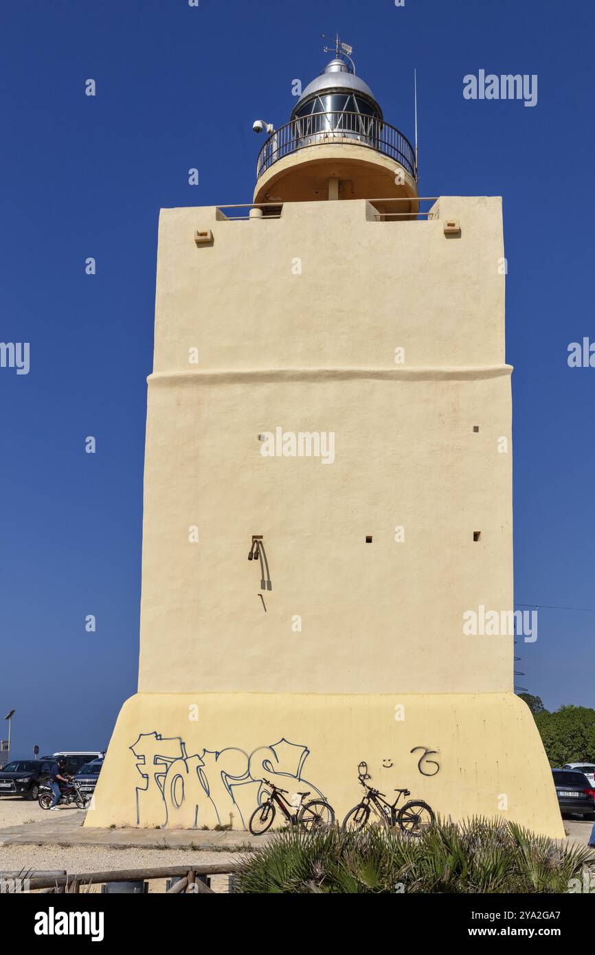 Yellow lighthouse with graffiti on the base in front of a clear blue ...