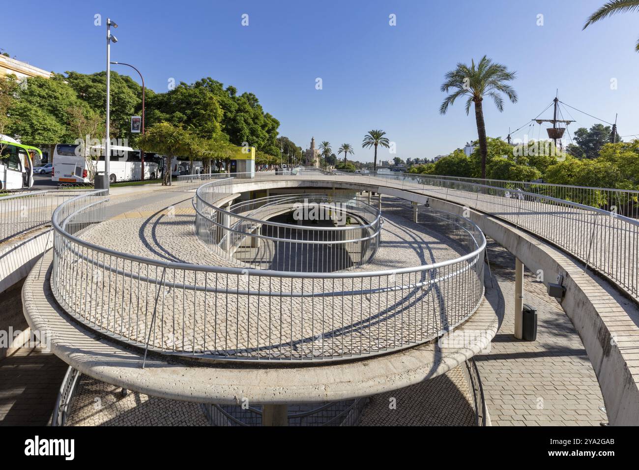 Modern pedestrian bridge with circular paths and palm trees in sunny ...