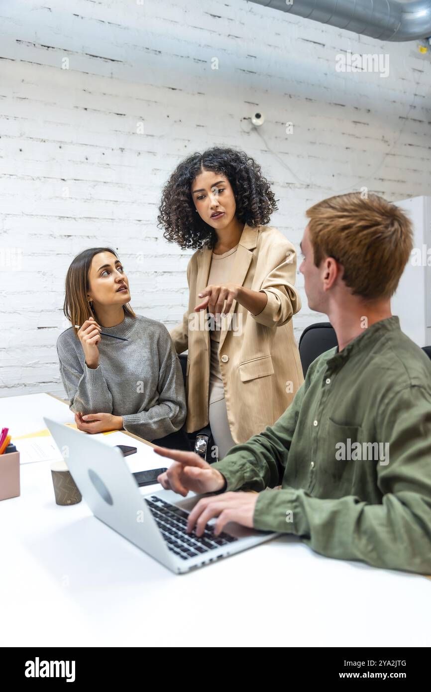 Vertical photo of an hispanic female boss scolding two employees in a ...