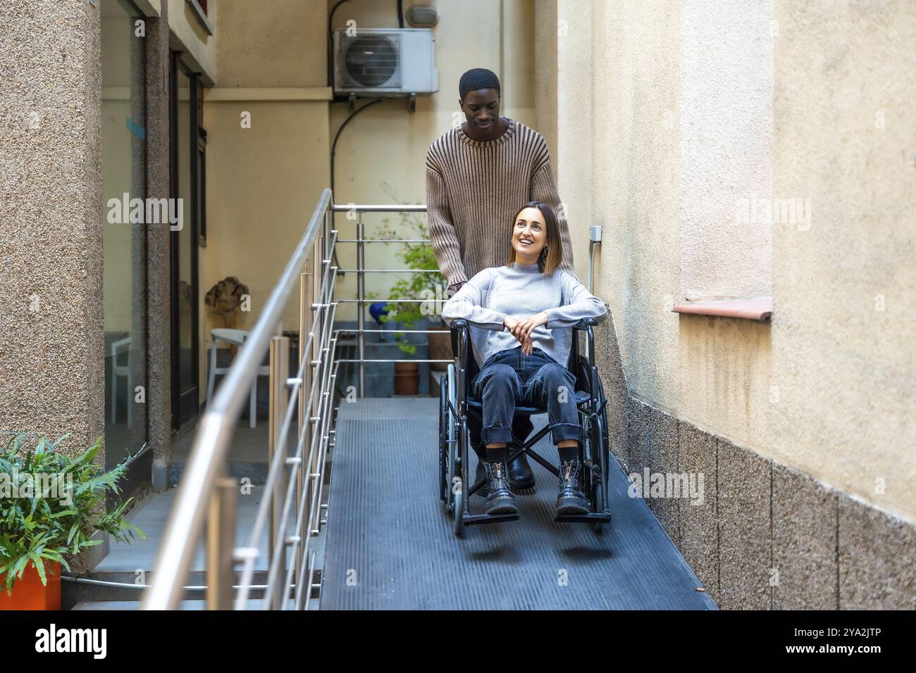 African man pushing the wheelchair of disabled colleague leaving a ...