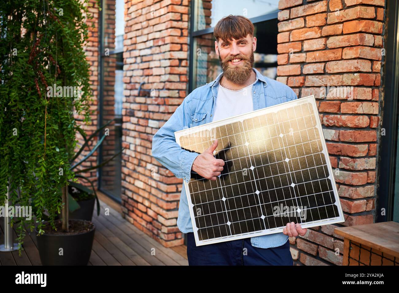 Portrait of bearded man holds solar panel, giving thumbs up, standing ...