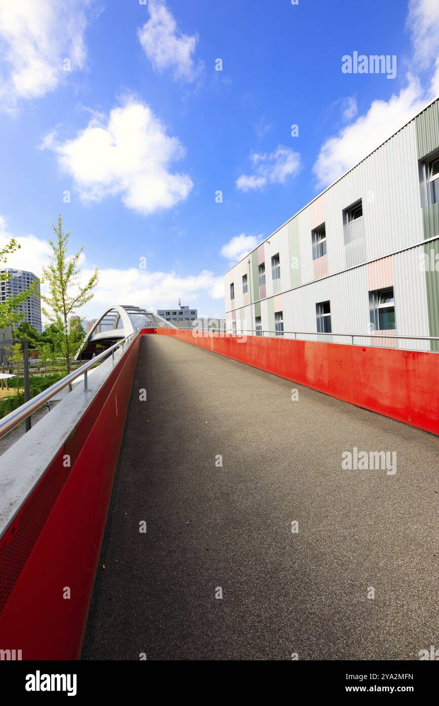 Bridge with red railings and blue sky next to modern buildings ...