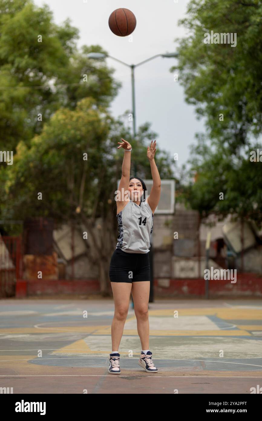 Frontal portrait of a female basketball player shooting the ball at the ...