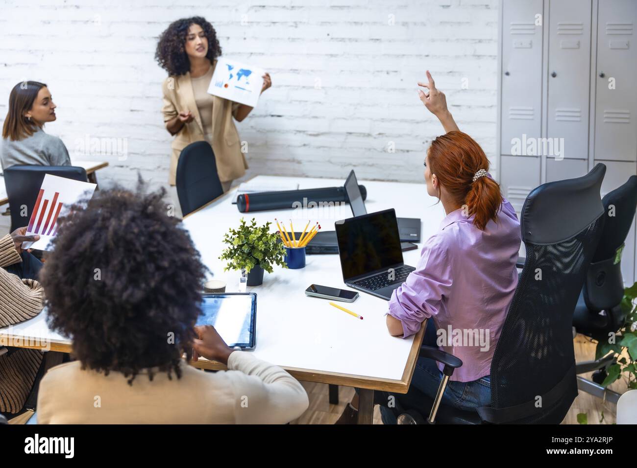 Woman asking question during a data presentation of a female colleague ...