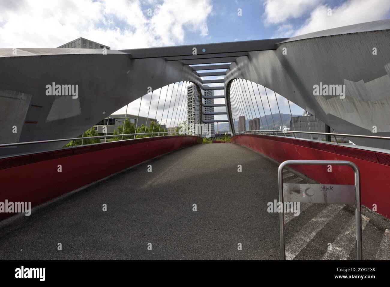 Modern pedestrian bridge with striking steel architecture and cloudy ...