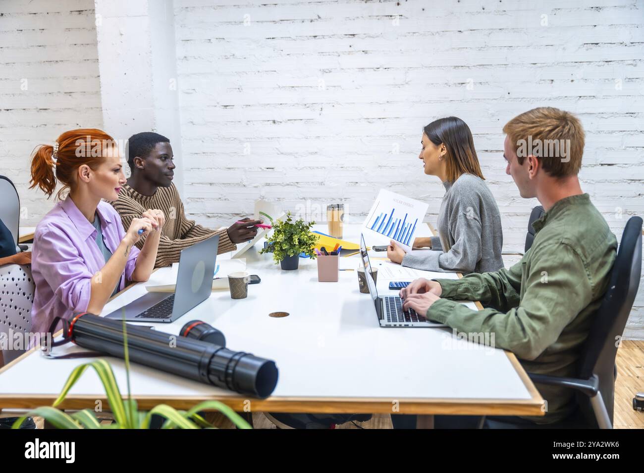 Group of diverse engineers talking and analyzing graphs in a coworking ...