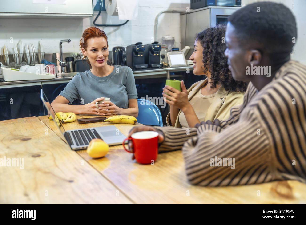 Multi-ethnic coworkers eating during coffee break in the cafeteria of a modern coworking Stock ...