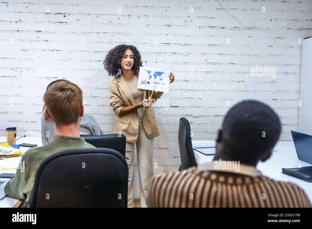 Caucasian young woman showing an infographic during a coworking meeting ...