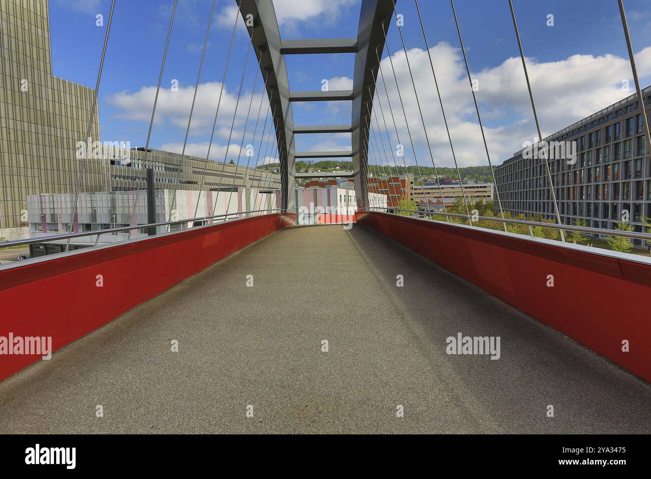 Modern bridge in an urban setting with red railings and blue sky ...