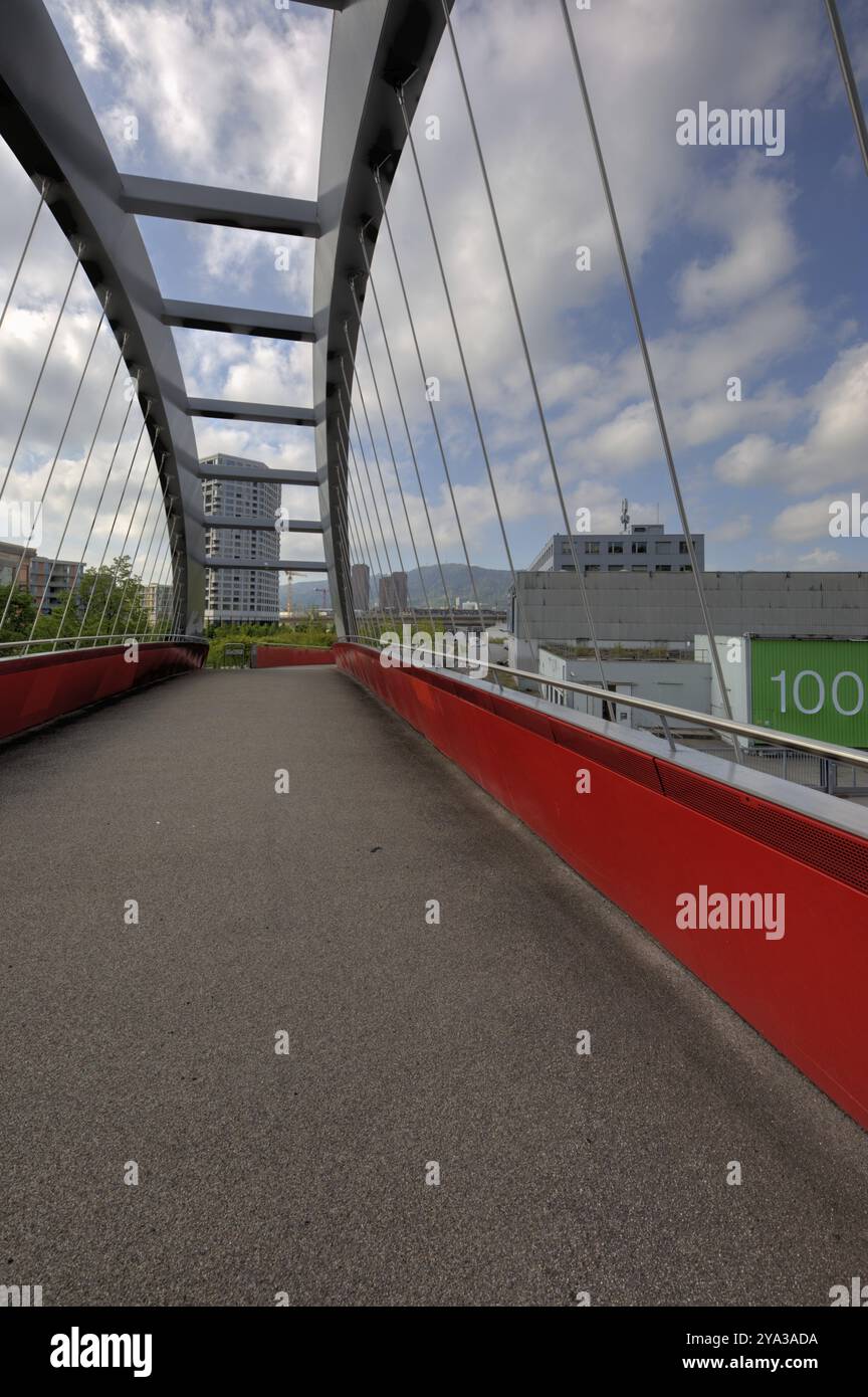 Modern bridge with red railing and overcast sky in urban environment ...