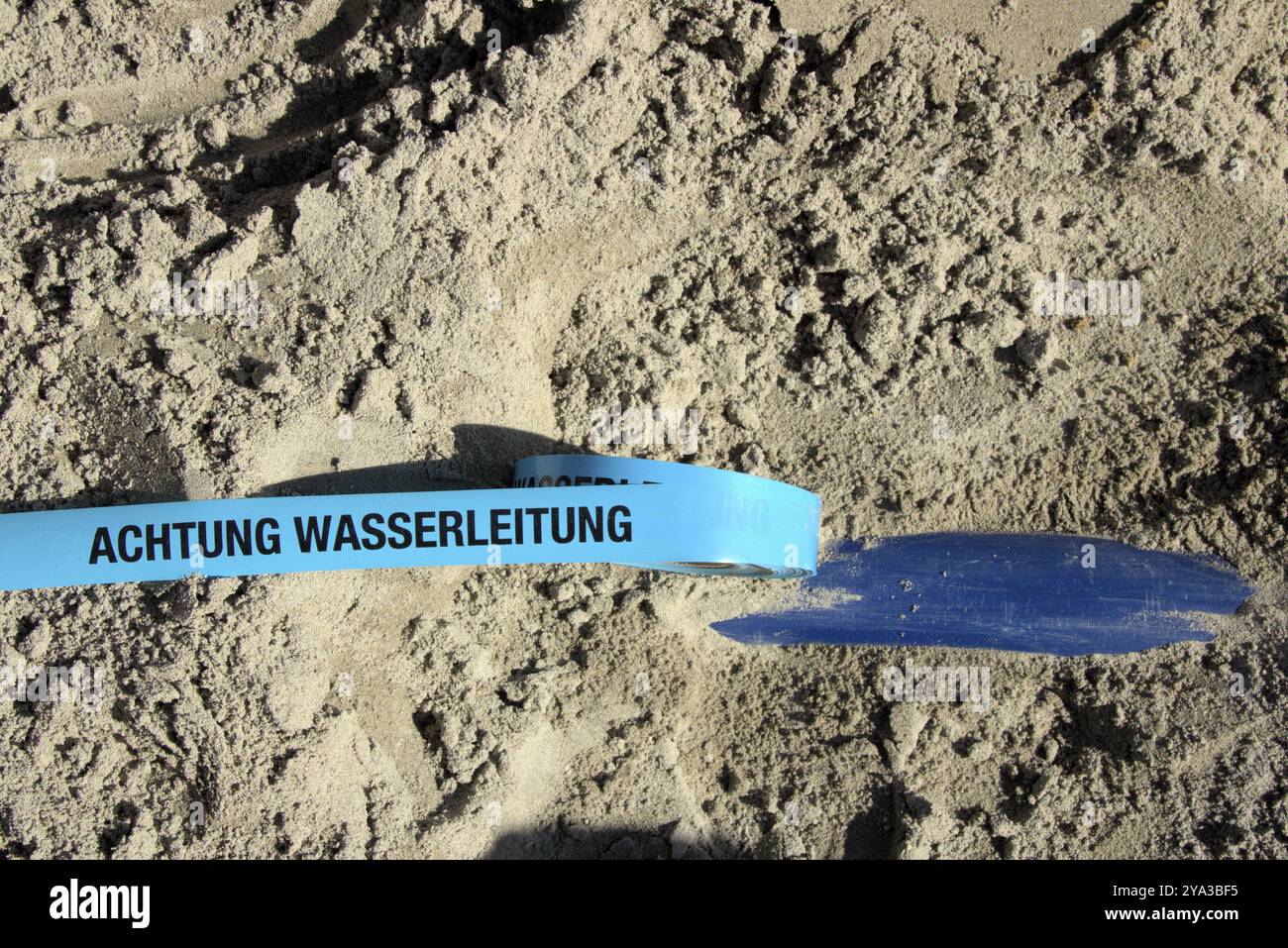 Tape indicating a water pipe in an excavation pit Stock Photo - Alamy
