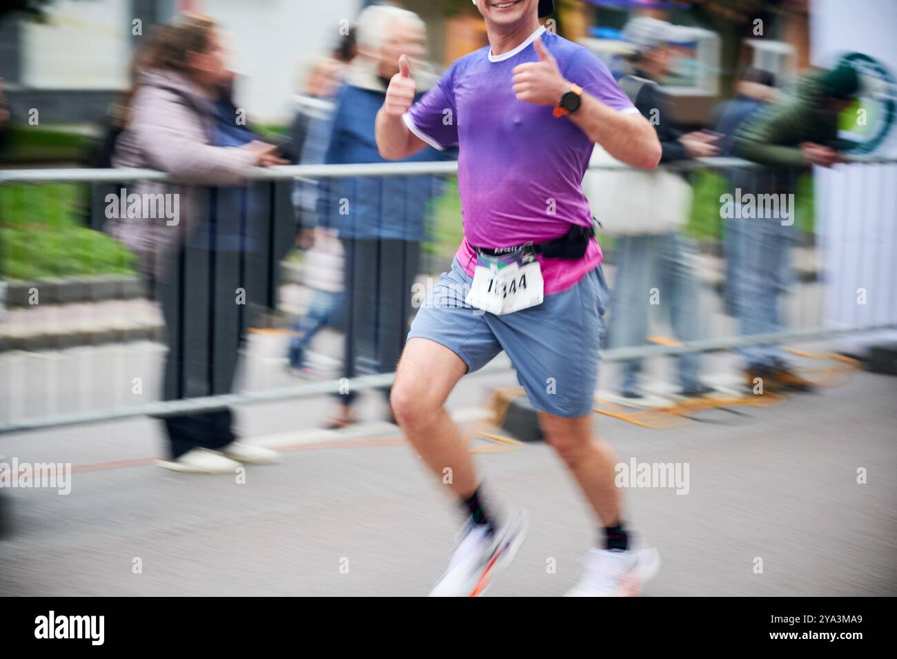 Runner gives two thumbs up as he races past spectators, his confident ...