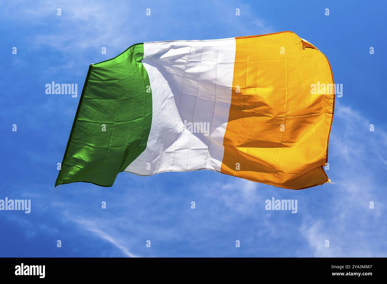 Irish flag fluttering in a brisk breeze against a bright blue sky ...