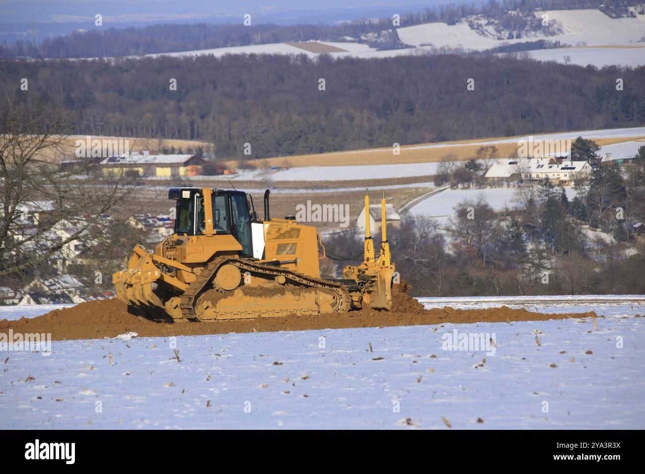 Caterpillar drives over a field in winter and spreads soil Stock Photo ...