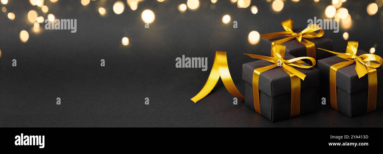 There are three elegant black gift boxes adorned with shiny gold ...