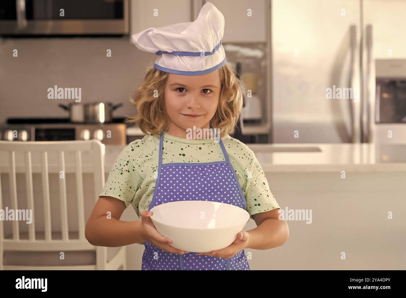 Child chef cook with cooking plate. Funny child stand at kitchen table ...